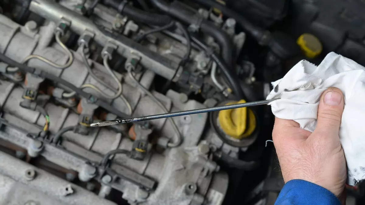 Auto Mechanic Checking Nivel de aceite de motor.