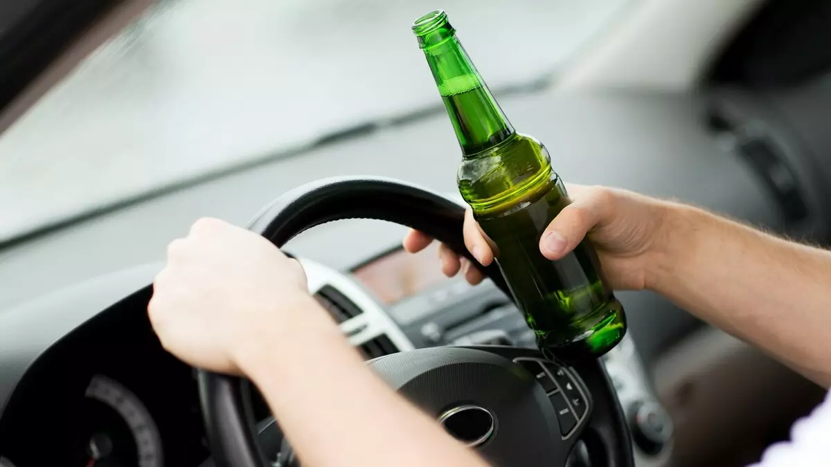 Homme buvant de l'alcool tout en conduisant la voiture