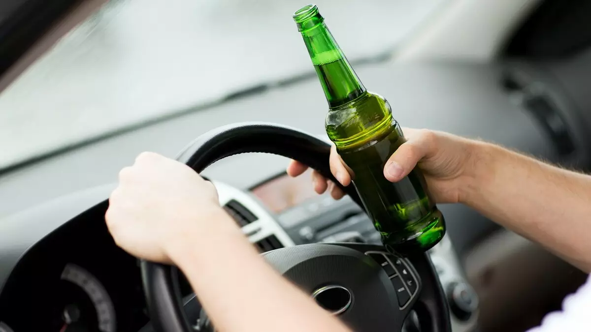 Man drinken alkohol by it riden fan 'e auto