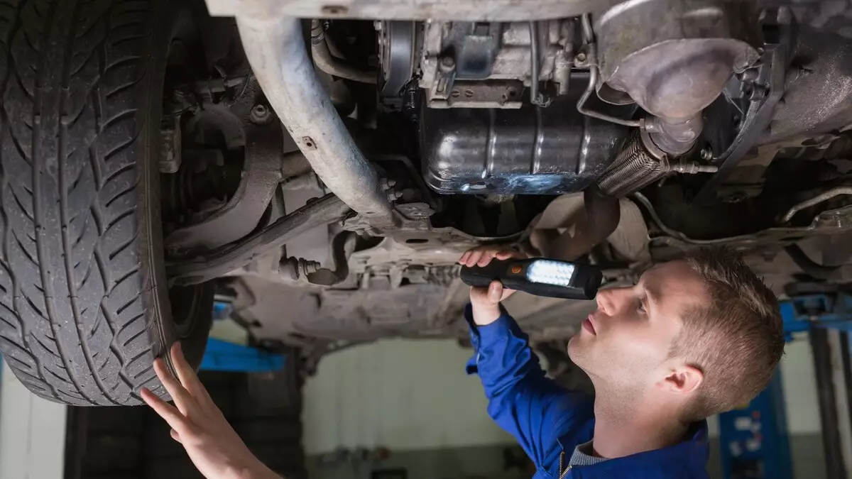 Vīriešu mehāniķis, kas pārbauda automašīnu, izmantojot zibspuldzi