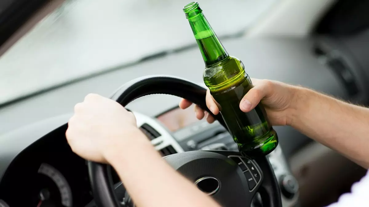 Človek pitie alkoholu počas jazdy autom