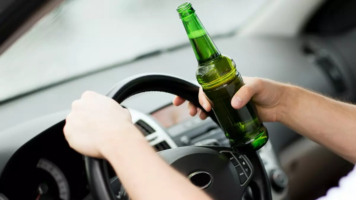 Čovjek pije alkohol dok vozi automobil