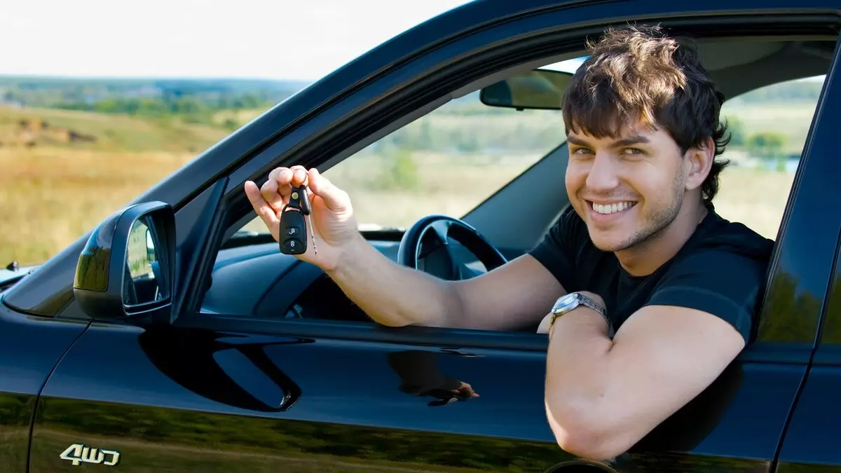 Glad mand, der viser nøgler i bil